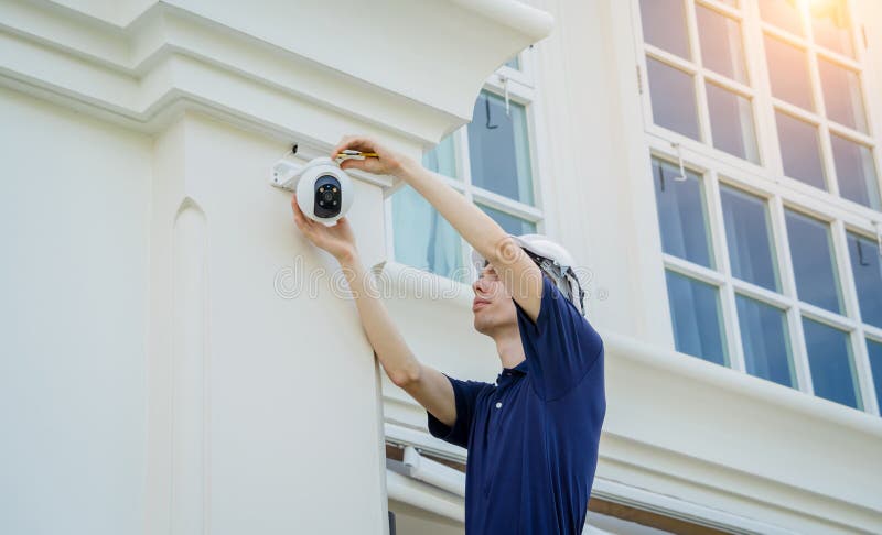 A Technician Installs a CCTV Camera on the Facade of a Residential ...