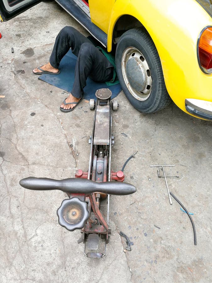 Technician Man Under Vihicle for Fixing and Maintenance Old Yellow Car ...