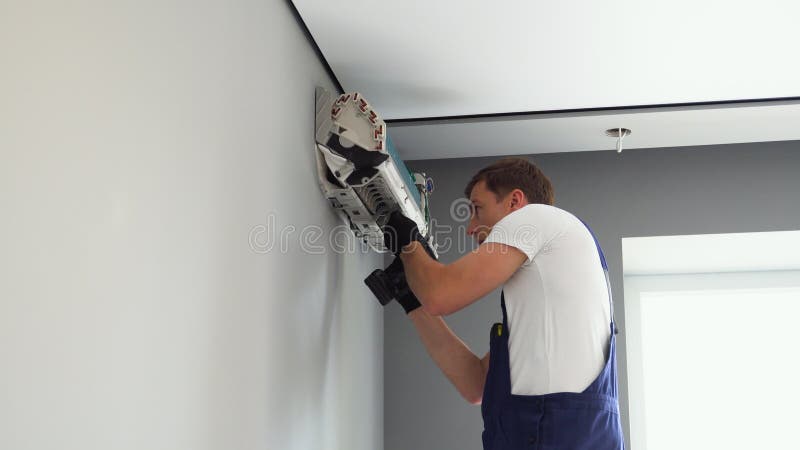 Technician Man Worker Repairing and Installs Air Conditioner on Grey ...