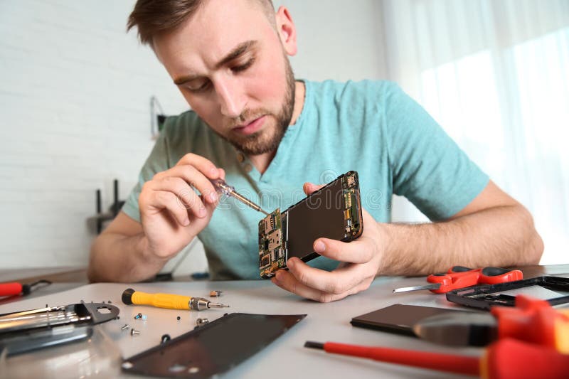 Technician Repairing Mobile Phone at Table in Workshop Stock Photo ...