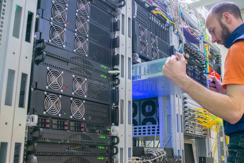 A Technician Repairs the Central Router. a Man Works in a Server Room ...