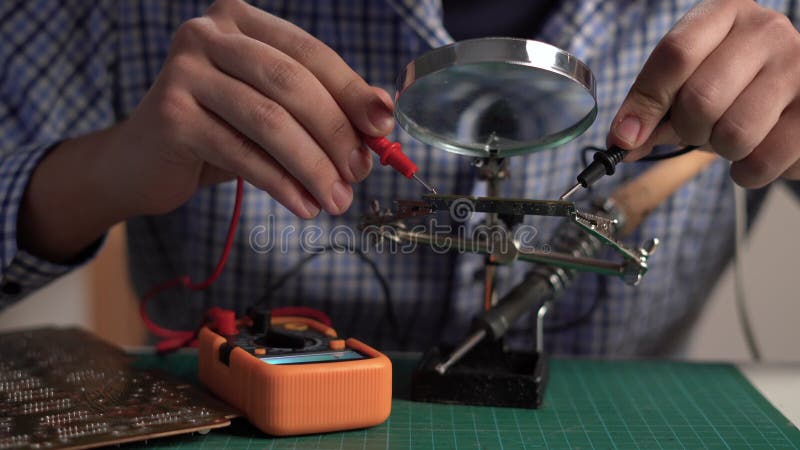 Guy Checking Circuit Board with Multimeter on Table at Home and ...