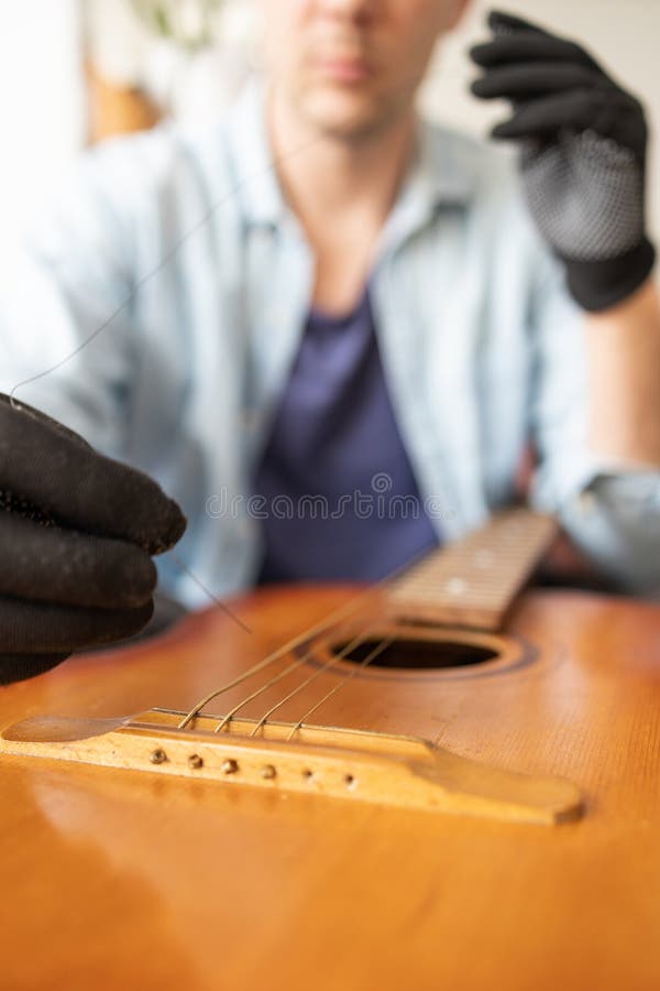 Repair of an Old Guitar. the Man Inserts the Strings into the Holes in ...