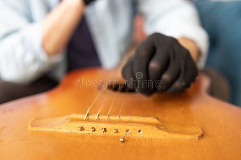 Repair of an Old Guitar. the Man Inserts the Strings into the Holes in ...