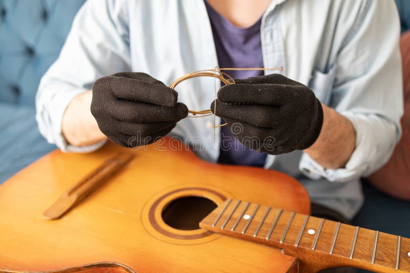 Repair of an Old Guitar. the Man Inserts the Strings into the Holes in ...