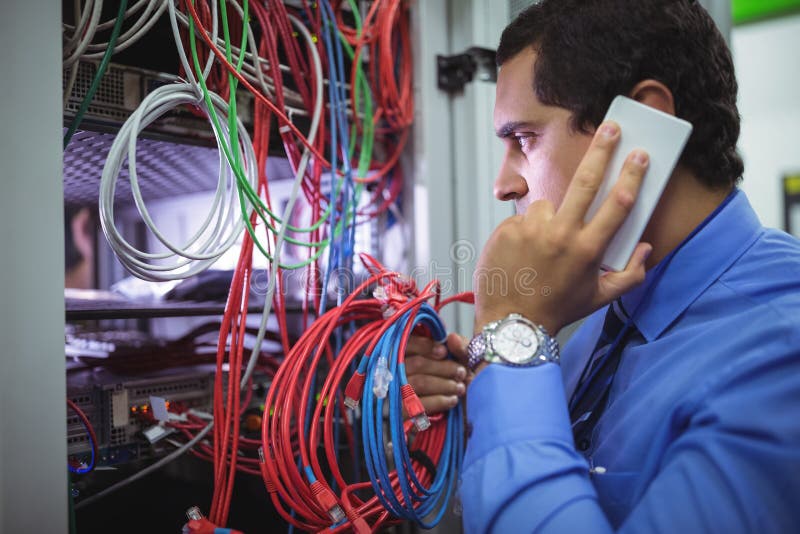Technician Talking on Mobile Phone while Checking Cables Stock Photo ...