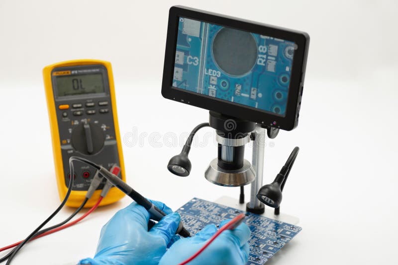 Technician Inspecting Circuit Board with Multimeter and Microscope ...