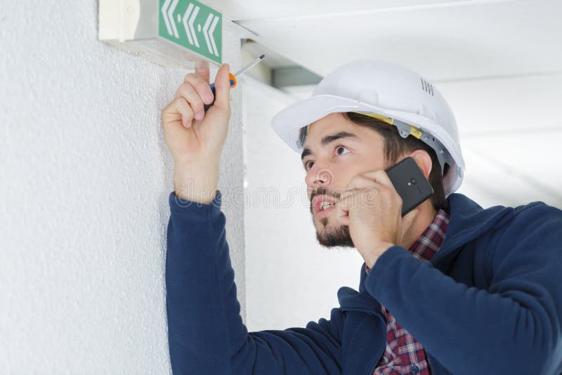 Technician Using Phone while Fixing Exit Sign Stock Photo - Image of ...