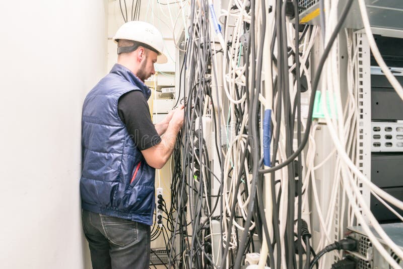 A Technician Connects a Fiber Optic Internet Cable in a Server Room. a ...