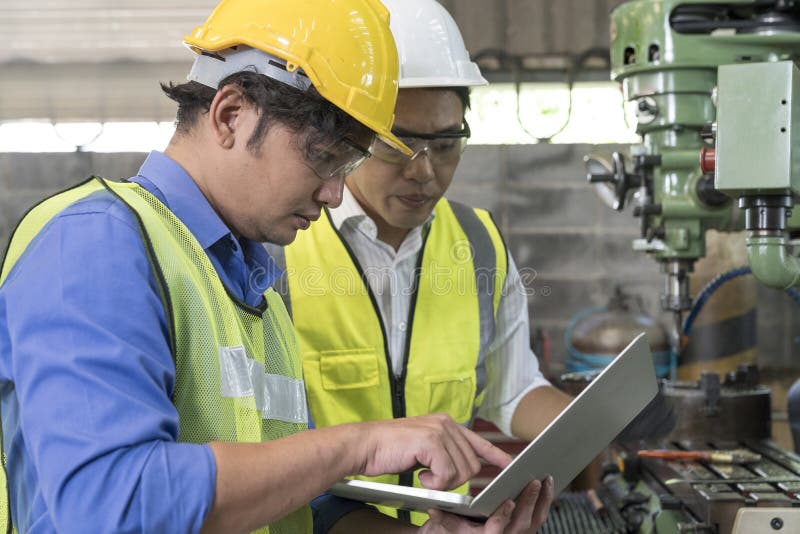 A Technician with a Wrench and Computer Laptop. Factory Workers Using ...