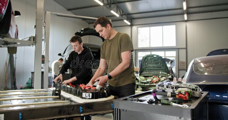 Technicians Assembling High-Voltage Battery Component for Electric Car ...