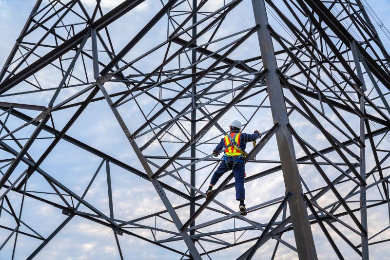 Workers Wearing Safety Harnesses are Working at High Voltage Pylons for ...