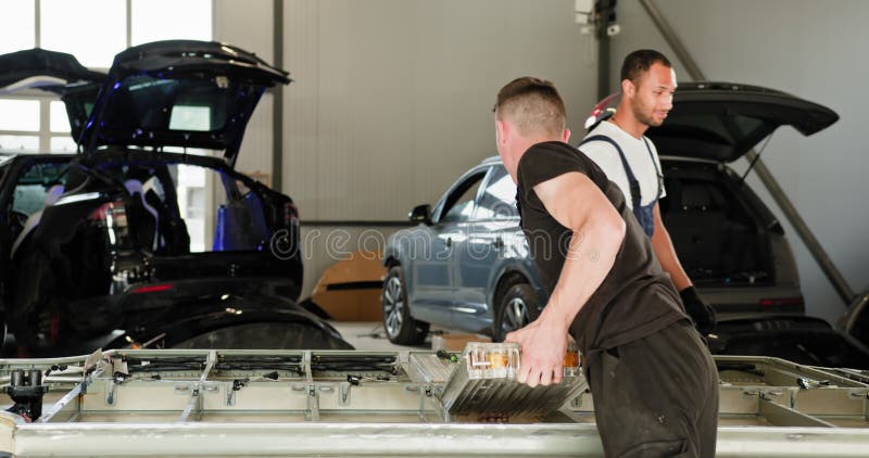 Technicians Working on Electric Car Battery Module in Workshop Stock ...