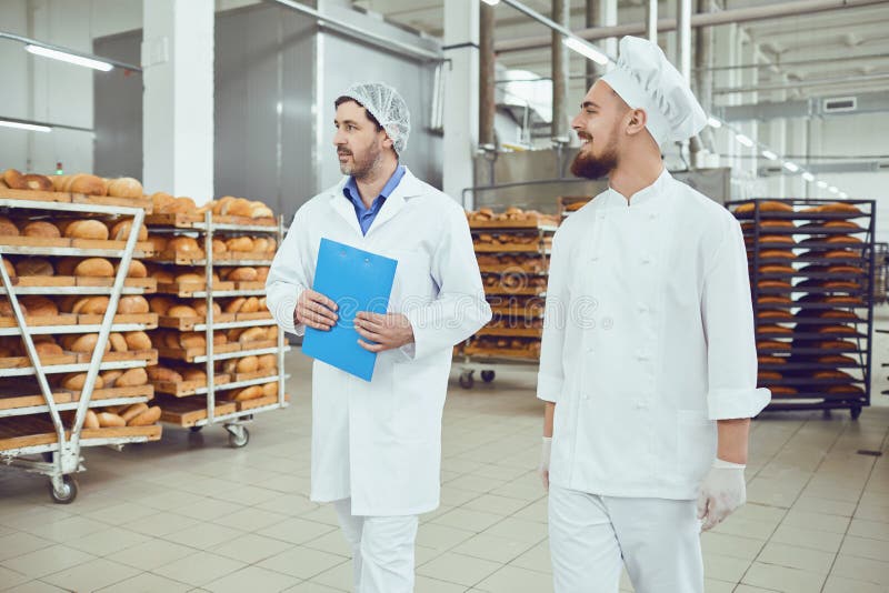 The Technologist and Baker Speak in a Bread Factory. Stock Photo ...