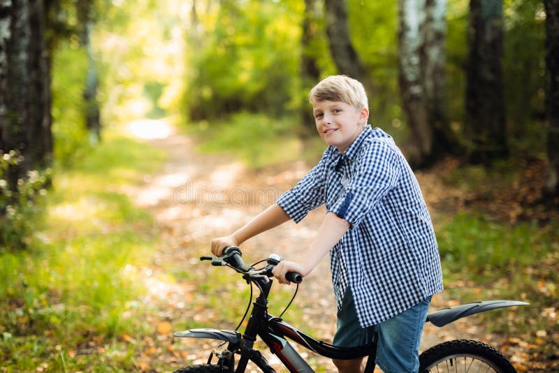 Teen Boy Rides a Bicycle Along a Path in the Forest. the Cyclist Rides ...