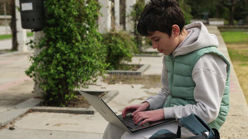 Teen Boy Studying Outdoors Using a Laptop in a Relaxing Environment ...