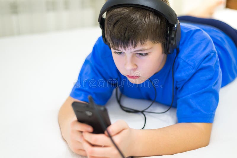 Teen Using Cell Phone with Headphones Stock Photo - Image of room ...