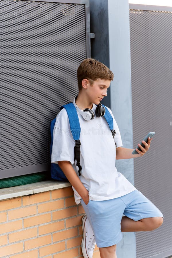 Teenage Boy with Backpack Using Mobile Phone while Relaxing Outdoors ...