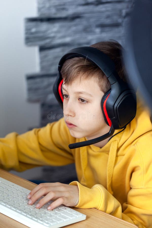 Teenage Boy in Headphones Uses Computer at Home at a Distance Learning ... Teenage Boy in Headphones Uses Computer at Home at a Distance Learning ...