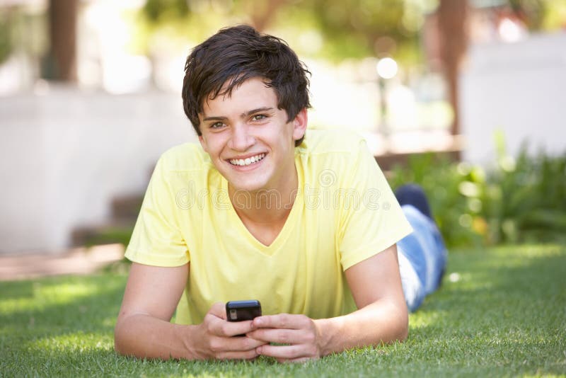 Teenage Boy Laying in Park Using Mobile Phone Stock Photo - Image of ...