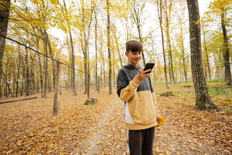 Teenage Boy Looking in Mobile Phone at Autumn Forest Stock Photo ...