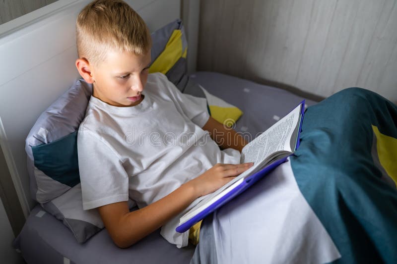 Teenage Boy Reading a Book before Bed Stock Image - Image of teenager ...