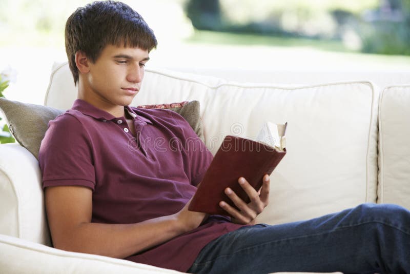 Teenage Boy Relaxing on Sofa at Home Reading Book Stock Photo - Image ...