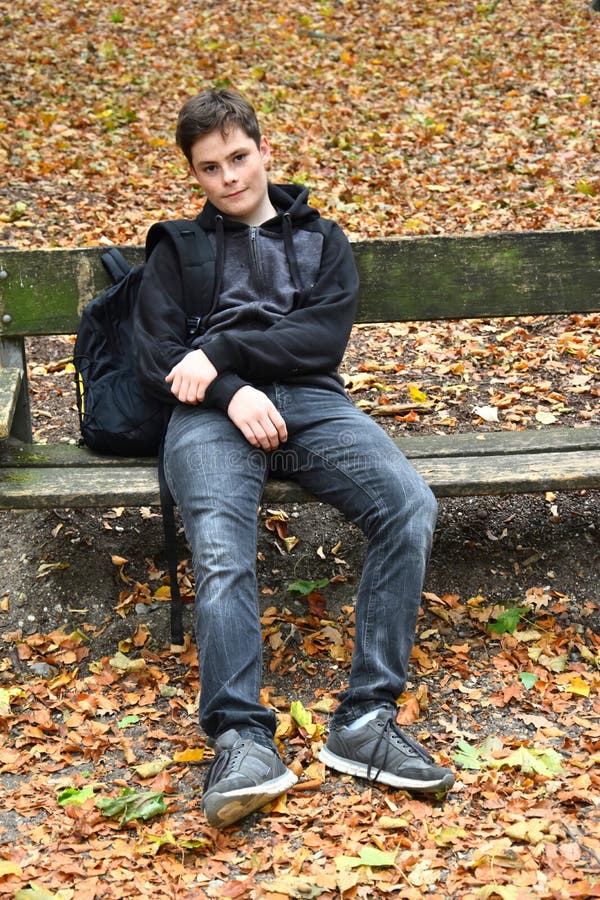 Boy resting on a bench stock image. Image of backpack - 129795215