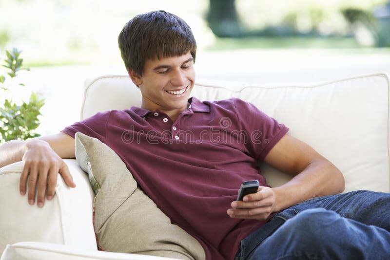 Teenage Boy Sending Text Message Sitting on Sofa Stock Photo - Image of ...