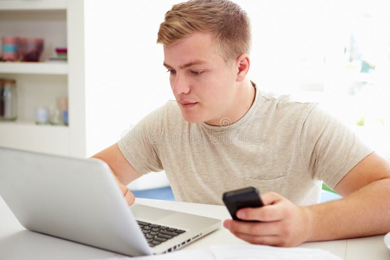 Teenage Boy Sending Text Message Whilst Studying on Laptop Stock Photo ...