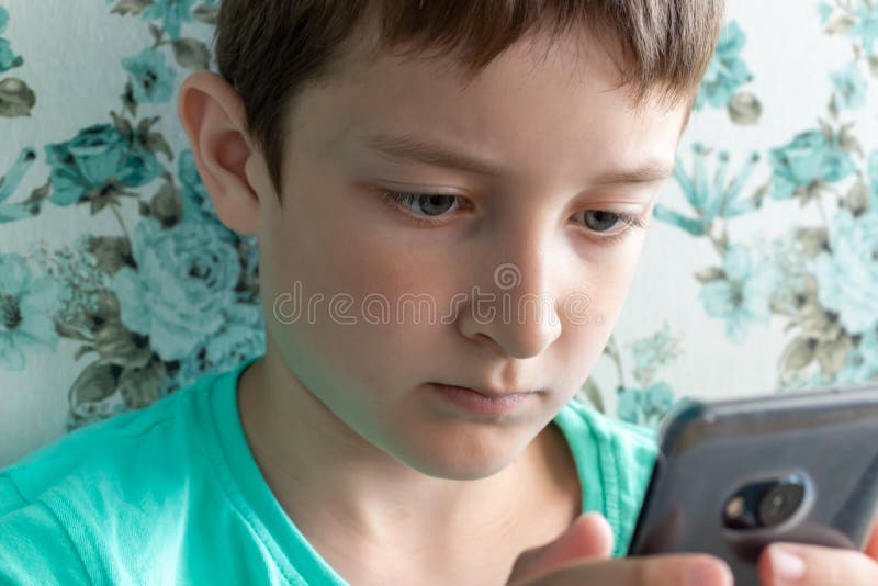 A Teenage Boy with Serious Face Playing Online Games Using Smartphone ...