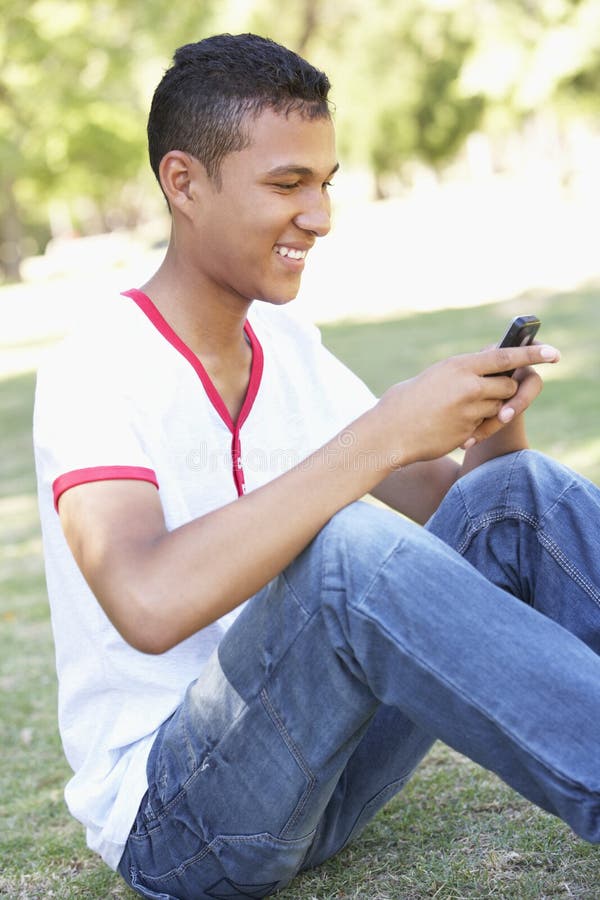 Teenage Boy Sitting in Park Using Mobile Phone Stock Image - Image of ...