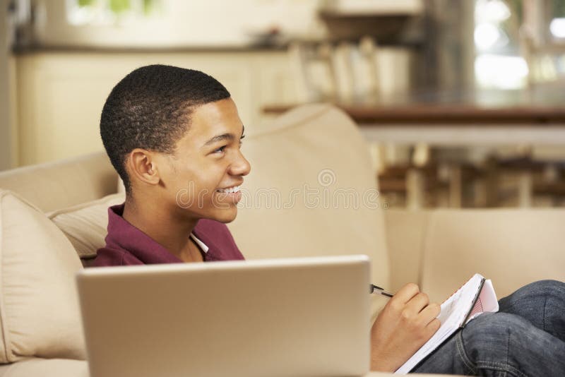 Teenage Boy Sitting on Sofa at Home Doing Homework Using Laptop ...