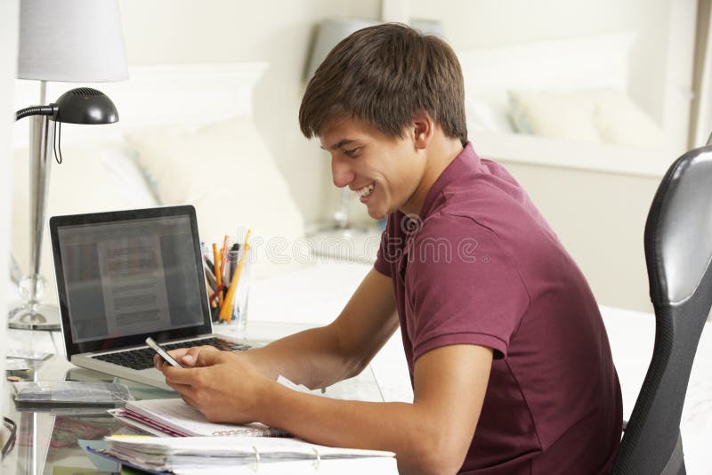 Teenage Boy Studying at Desk in Bedroom Using Mobile Phone Stock Photo ...