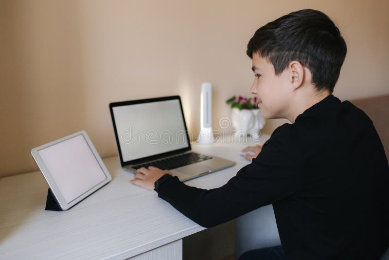 Teenage Boy Studying on Laptop and Watching Something on Tablet. Young ...