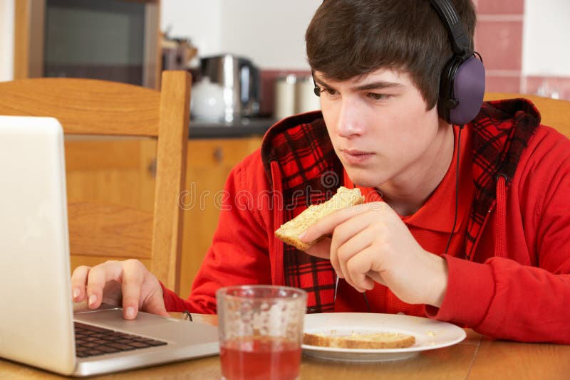 Teenage Boy Using Laptop Whilst Eating Breakfast Stock Image - Image of ...