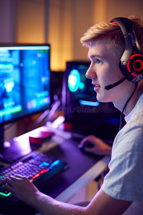 Teenage Boy Wearing Headset Gaming at Home Using Dual Computer Screens ...