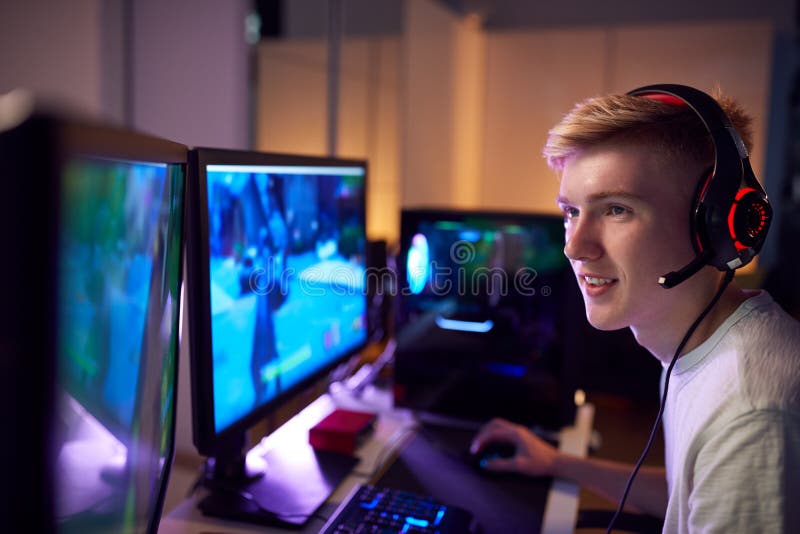 Teenage Boy Wearing Headset Gaming Home Using Dual Computer Screens ...