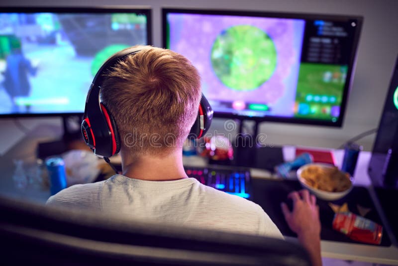 Teenage Boy Wearing Headset Gaming at Home Using Dual Computer Screens ...