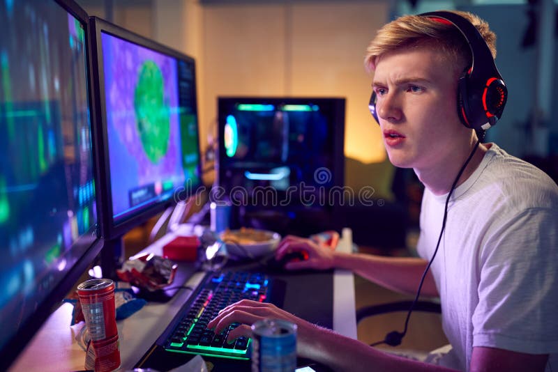 Teenage Boy Wearing Headset Gaming at Home Using Dual Computer Screens ...