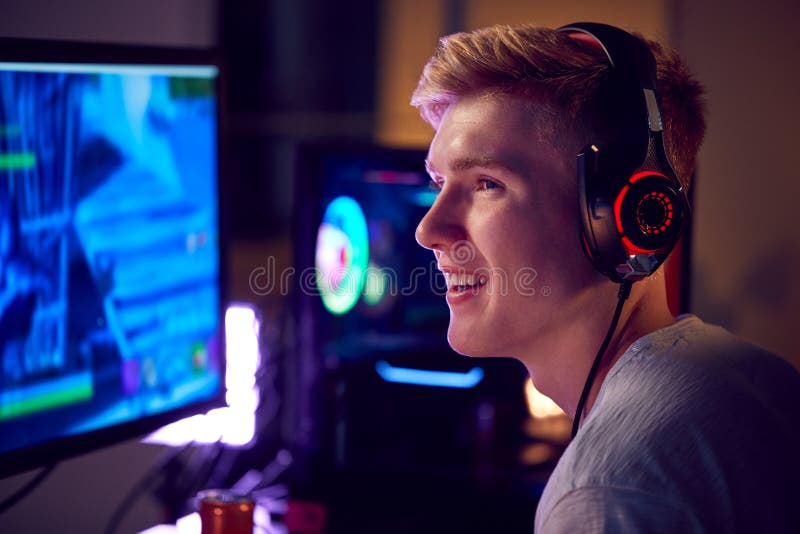 Teenage Boy Wearing Headset Gaming at Home Using Dual Computer Screens ...