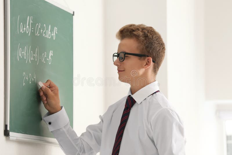 Teenage Boy Writing on Chalkboard in Classroom Stock Image - Image of ...