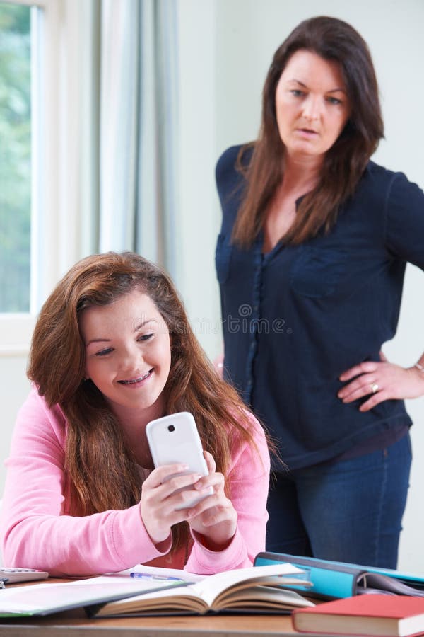 Teenage Daughter Using Mobile Phone Whilst Studying Stock Image - Image ...