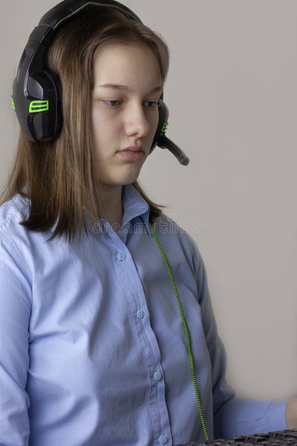 A Teenage Girl in a Blue Shirt and Headphones Sits in Front of a ... A Teenage Girl in a Blue Shirt and Headphones Sits in Front of a ...