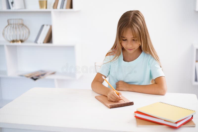 Teenage Girl Making Notes in Notepad, Doing Homework at Table at Home ...