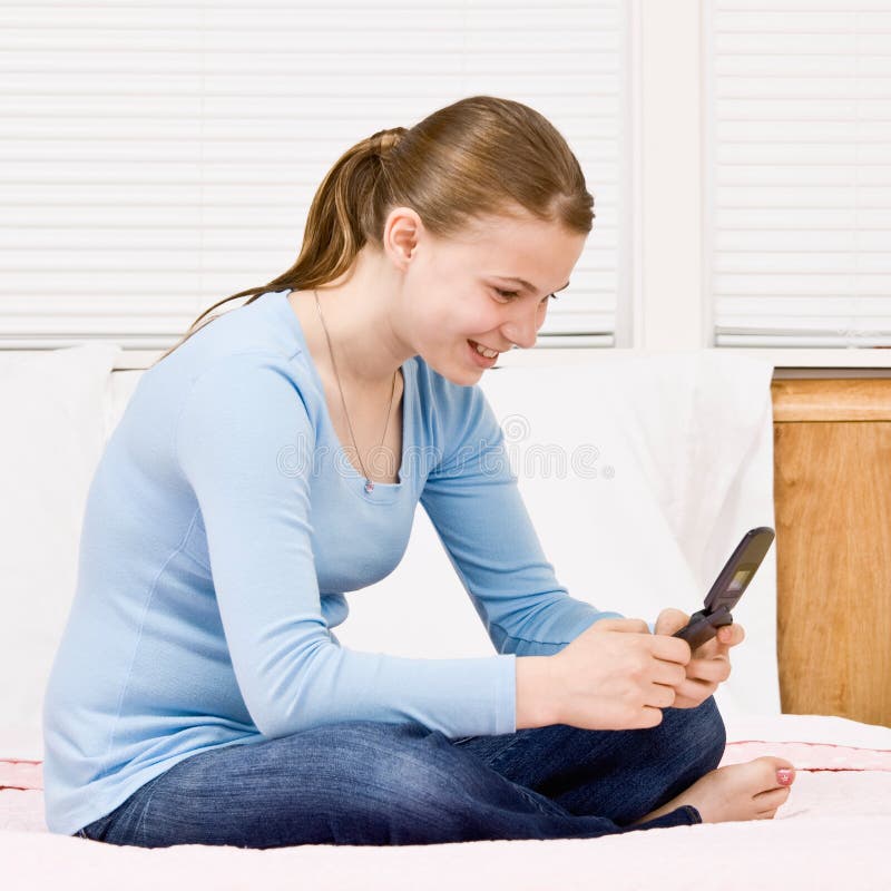 Teenage Girl Sitting on Bed Text Messaging Stock Image - Image of ...