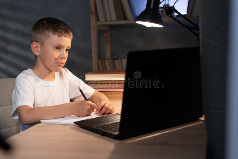 Teenager Boy Doing Homework at Home with Laptop and Writing Notes Late ...