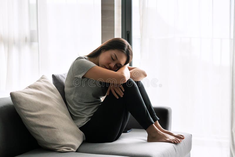 Teenager Girl With Depression Sitting Alone On Sofa At Home Sad
