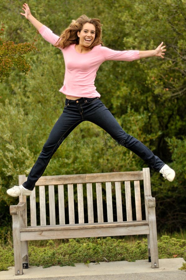 Teenager Jumping from a Bench with Arms Out Stock Photo - Image of ...