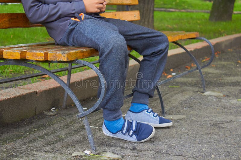 Teenager Sitting on a Bench,legs of a Boy Sitting on a Park Bench Stock ...